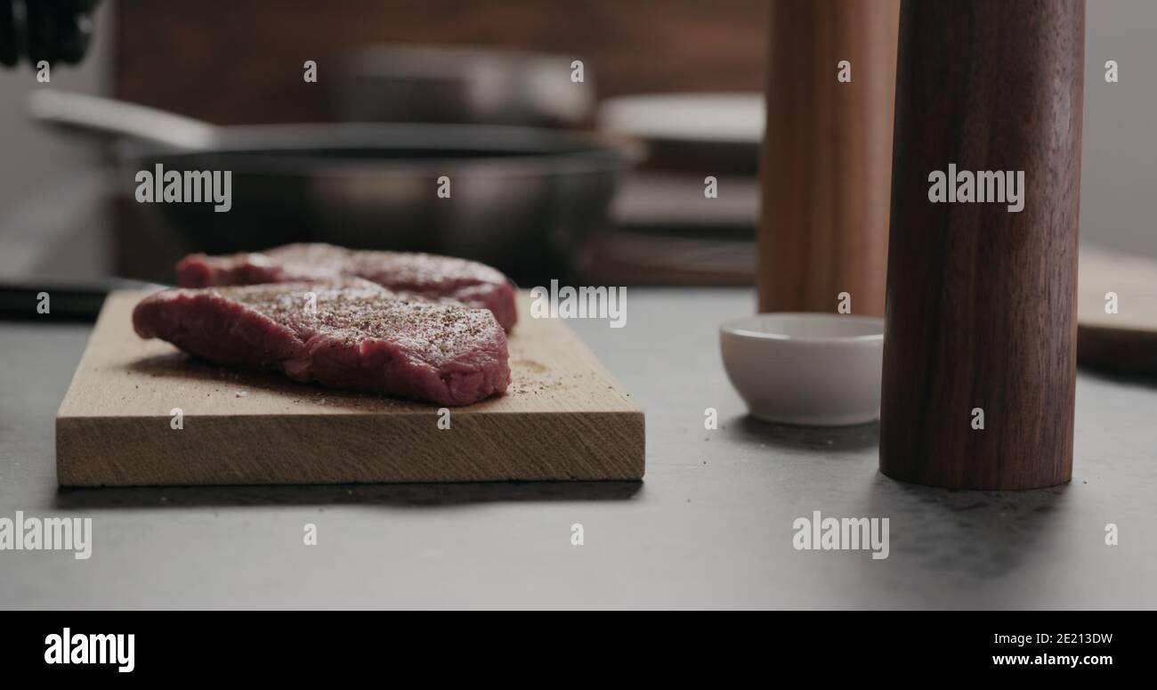 man grinding pepper on raw beef steak on oak board, wide photo Stock ...