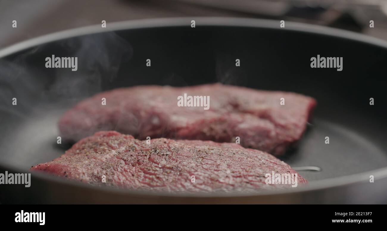 two beef steak pieces frying on nonstick pan, wide photo Stock Photo ...
