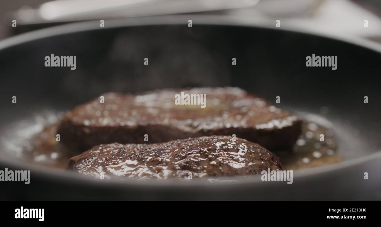 two beef steak pieces frying on nonstick pan, wide photo Stock Photo ...