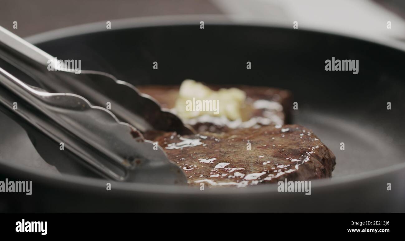 man flipping beef steak on nonstick pan with tongs, wide photo Stock ...
