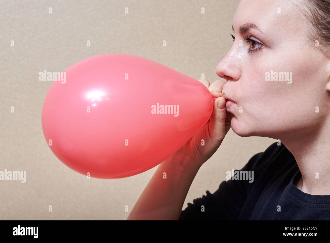 Young woman inflate a red balloon, the theme of holidays and parties ...
