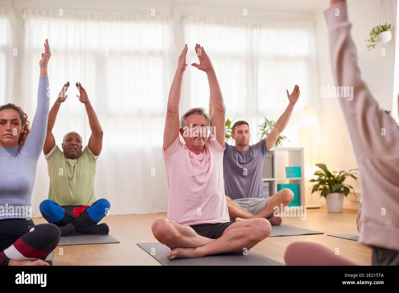 Group With Teacher Sitting On Exercise Mats Stretching In Yoga Class ...