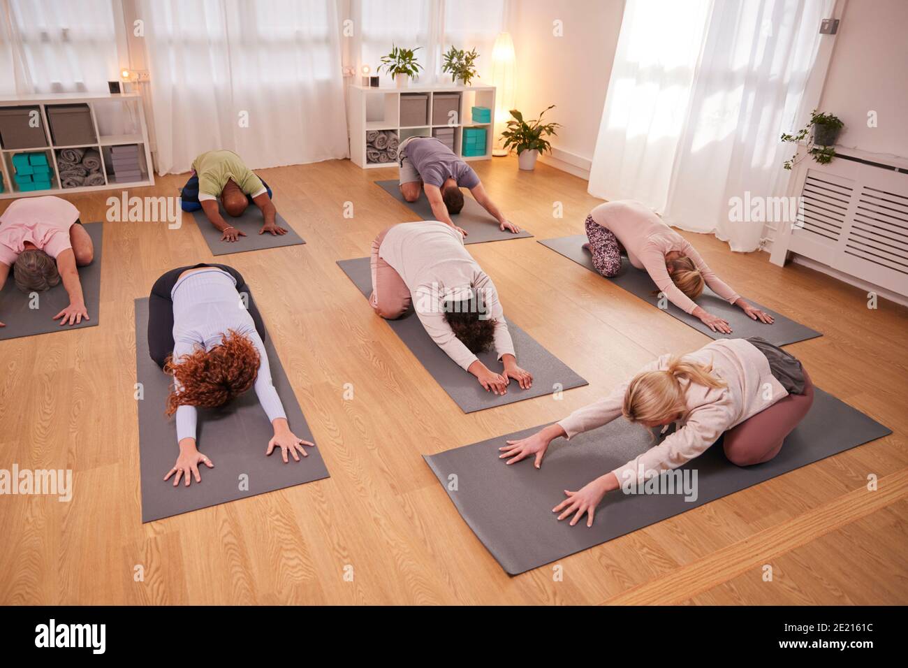 Teacher Helping Group Stretching On Exercise Mats In Yoga Or Fitness ...