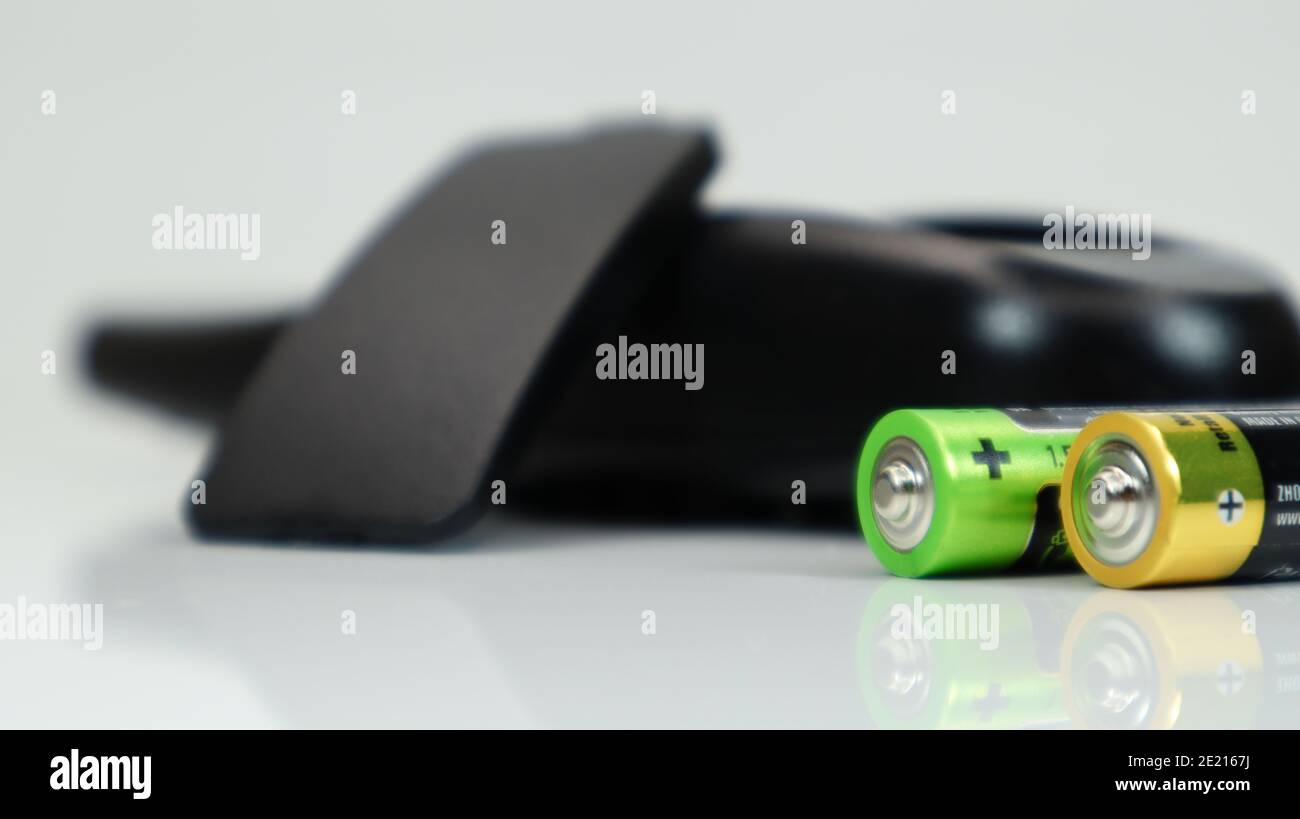 Black TV remote control with AAA alkaline batteries on a white ...