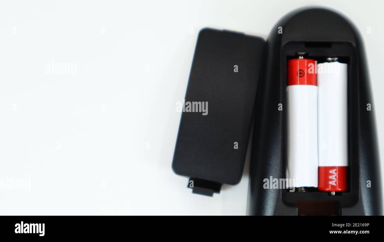 Black TV remote control with AAA alkaline batteries in red and white on ...