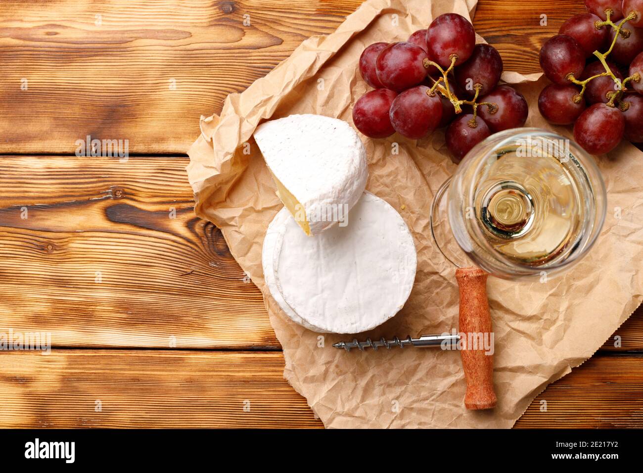Round white cheese with grapes on wooden table Stock Photo - Alamy