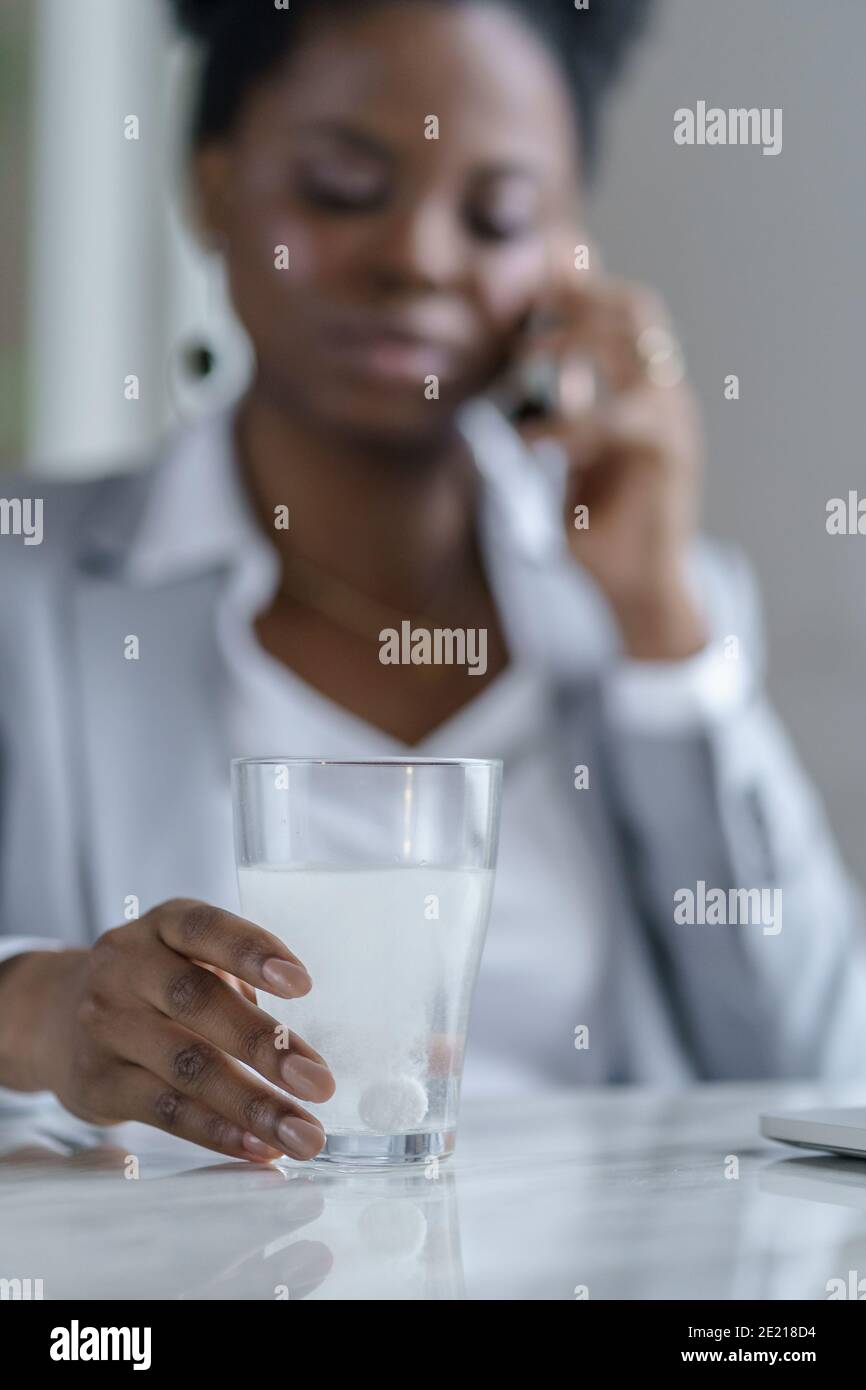 Afro woman holding sparkling water glass with dissolving effervescent ...