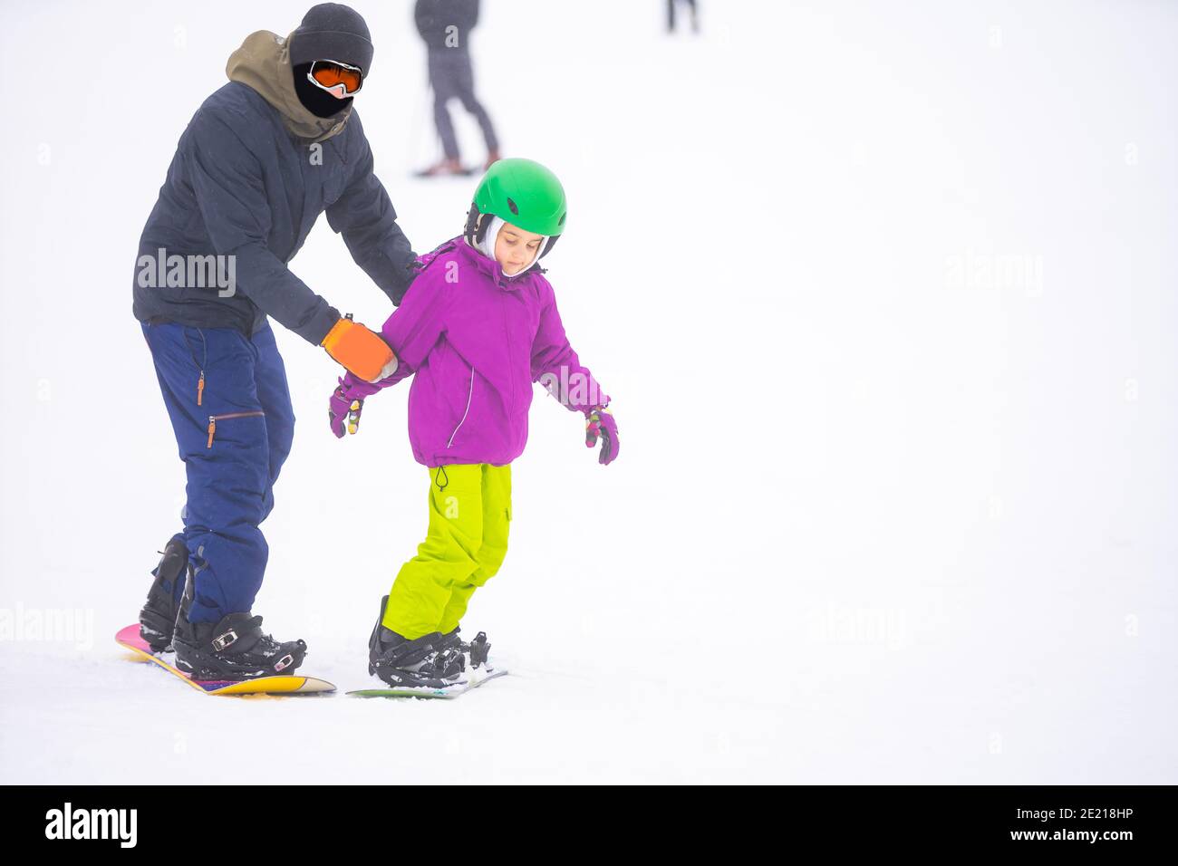 Instructors teach a child on a snow slope to snowboard Stock Photo - Alamy