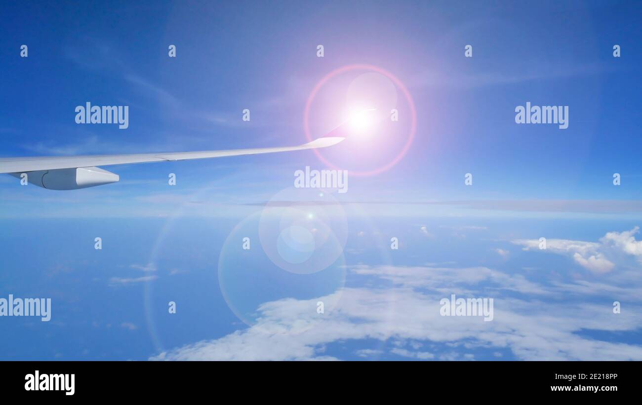 Sunlight reflects on the wings of a passenger plane while flying in the ...