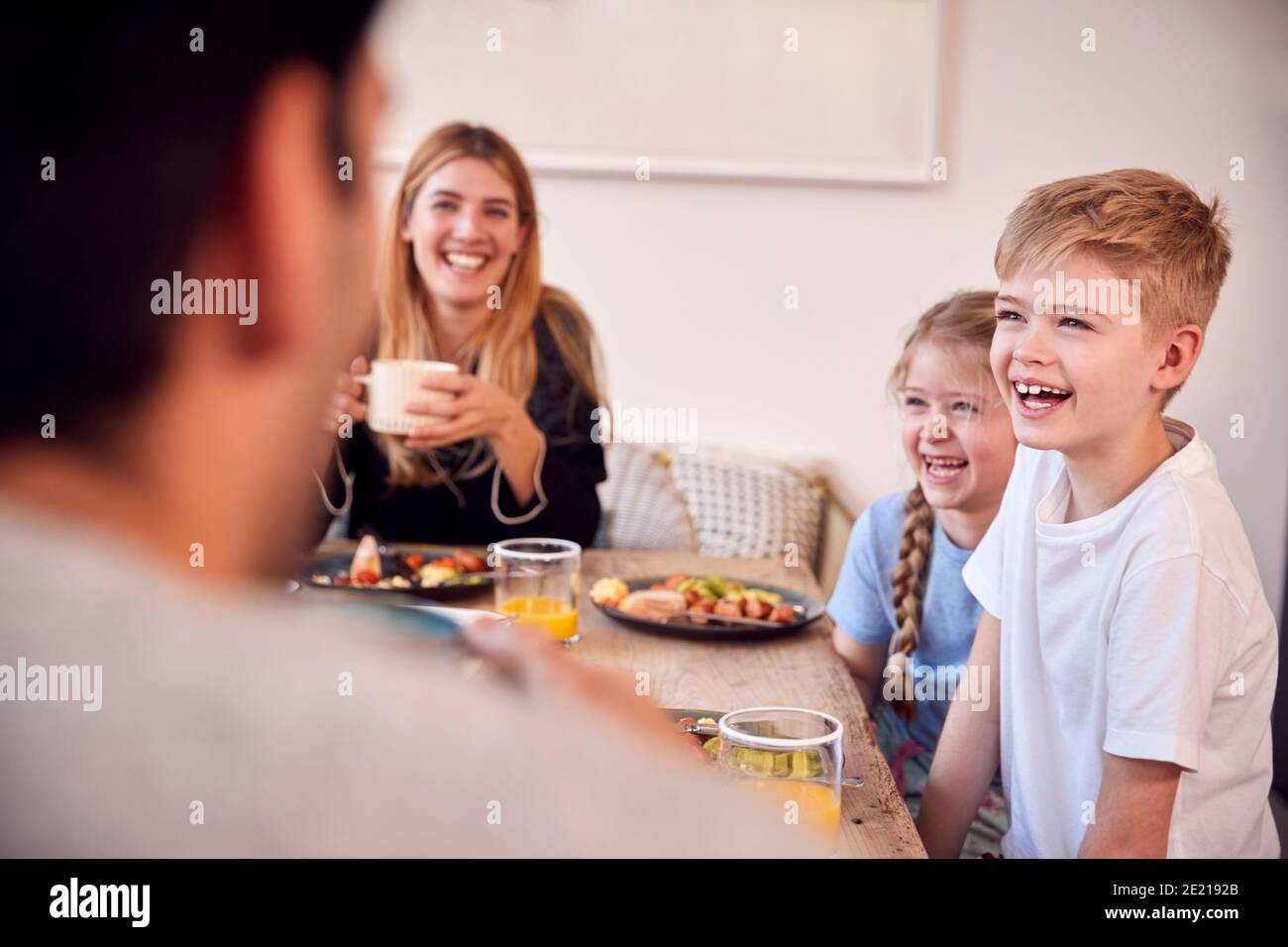 Family Sitting Around Table At Home In Pyjamas Enjoying Brunch Together ...