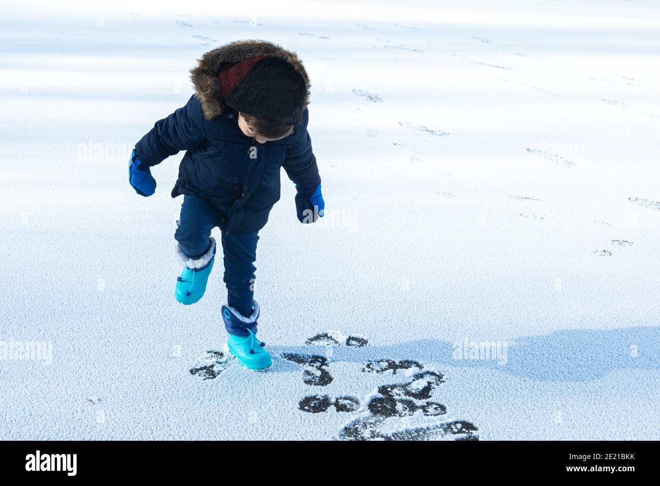a young child walks through the winter snowy landscape leaving ...