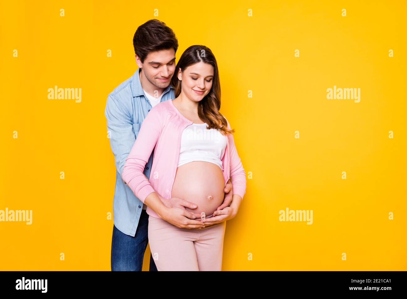 Photo of young couple stand hug pregnant woman look stomach wear casual ...