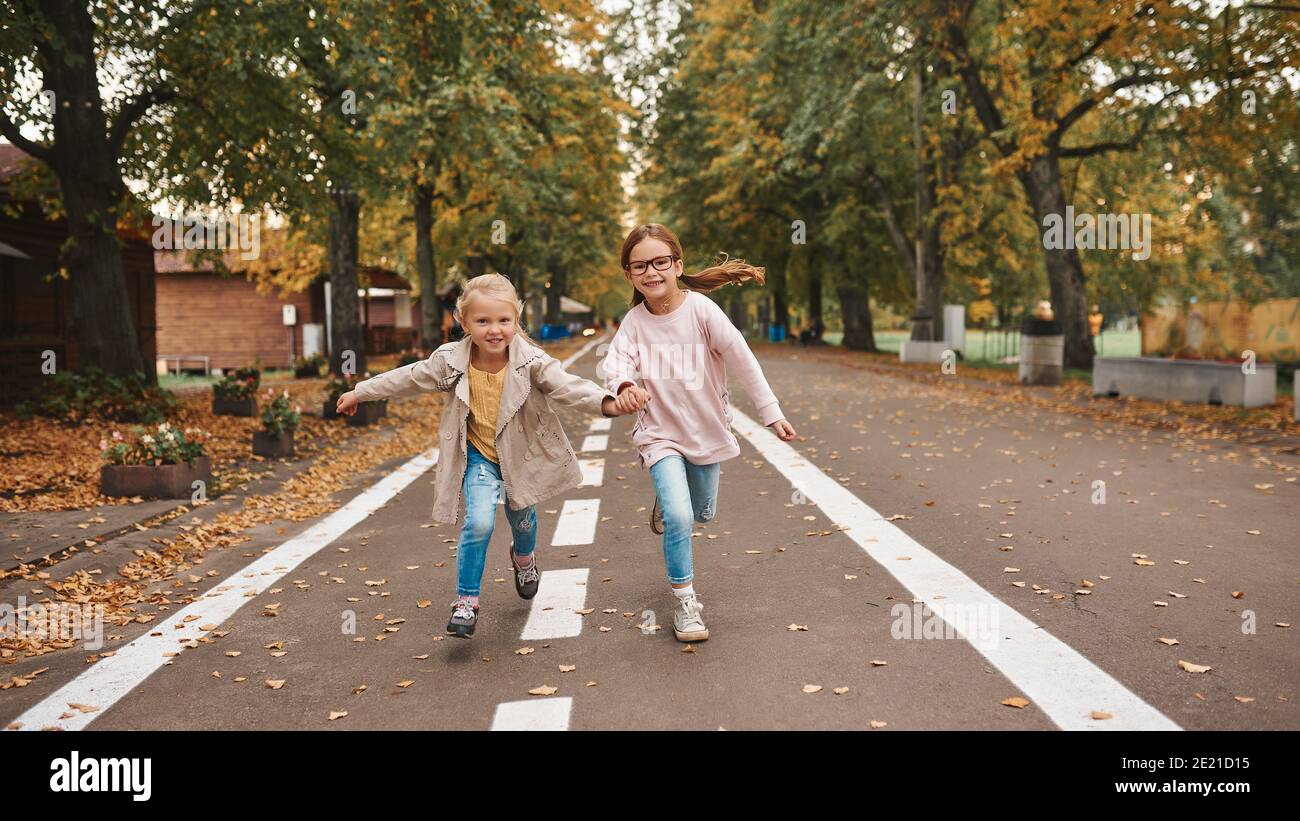 Two cute little girls having fun together and holding hands while ...