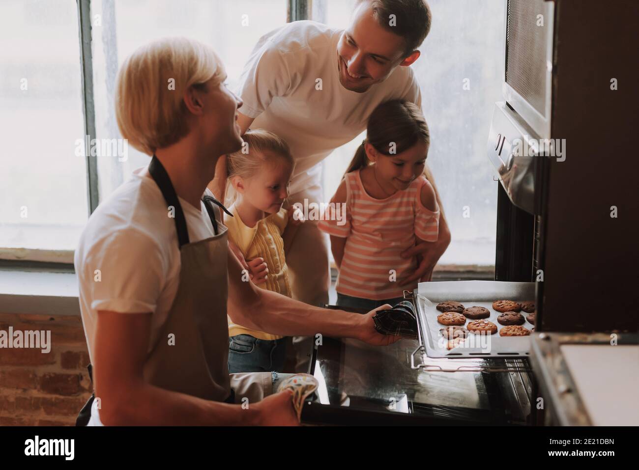 Gay couple with their adopted cute daughters cooking on kitchen. Lgbt ...