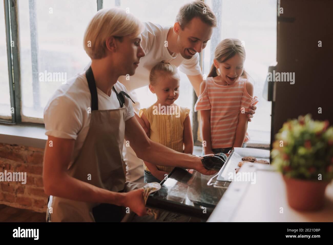Gay couple with their adopted cute daughters cooking on kitchen. Lgbt ...