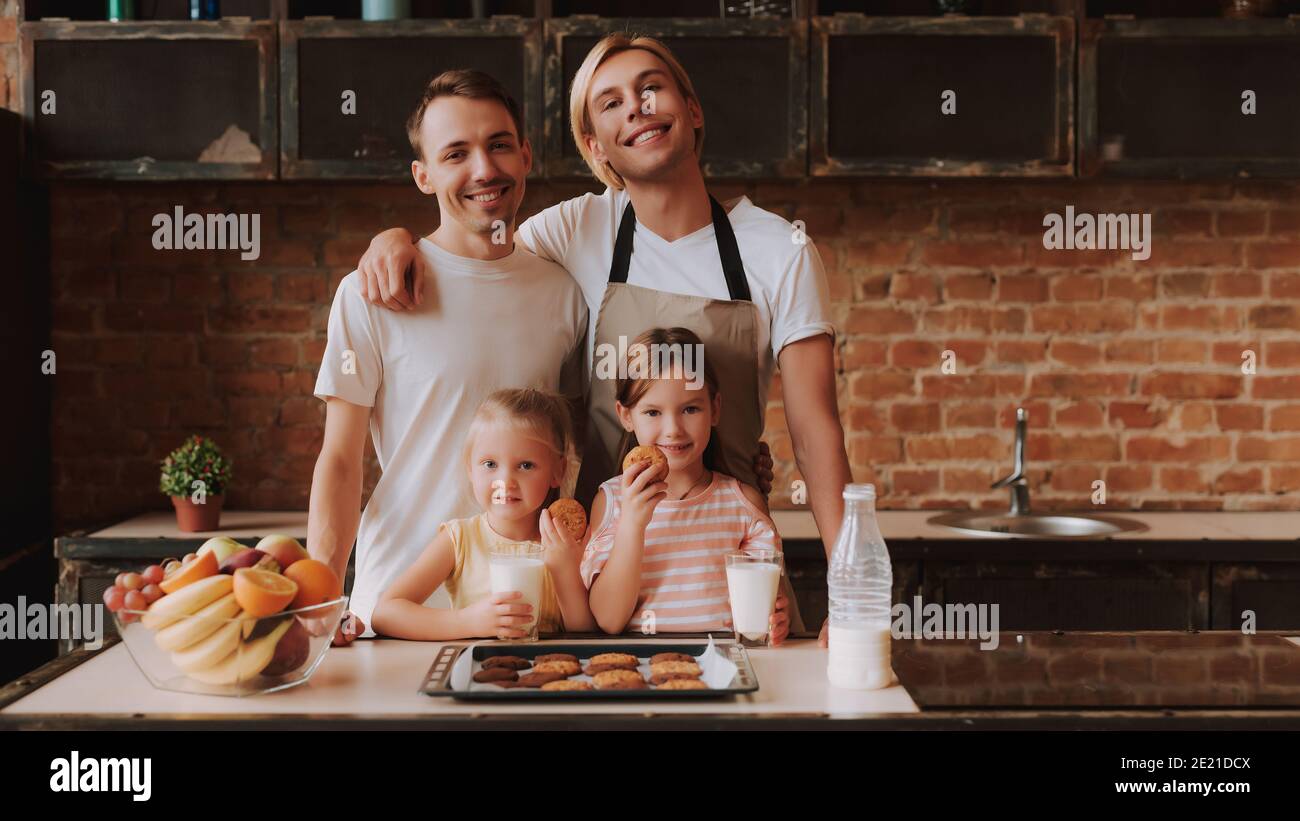 Gay couple with their adopted cute daughters cooking on kitchen. Lgbt ...