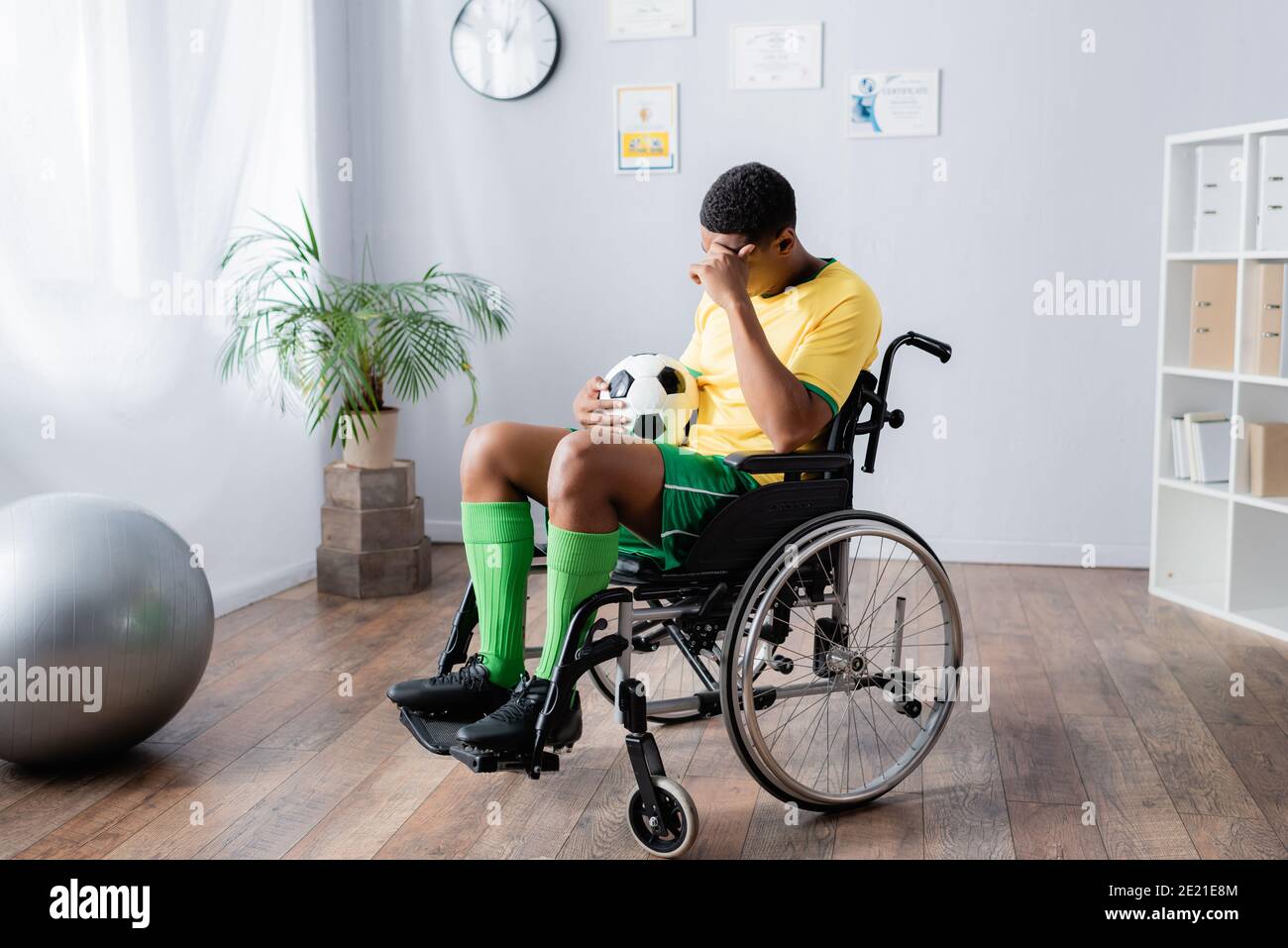 upset disabled african american sportsman in wheelchair holding ...