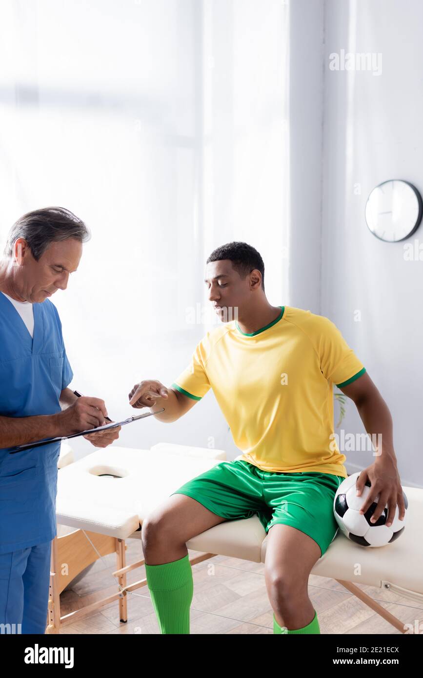 Football player sit on ball hi-res stock photography and images - Alamy