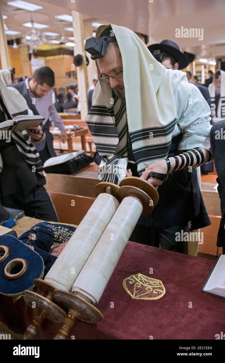 An orthodox Jewish man lifts the Torah slightly after being called to a ...