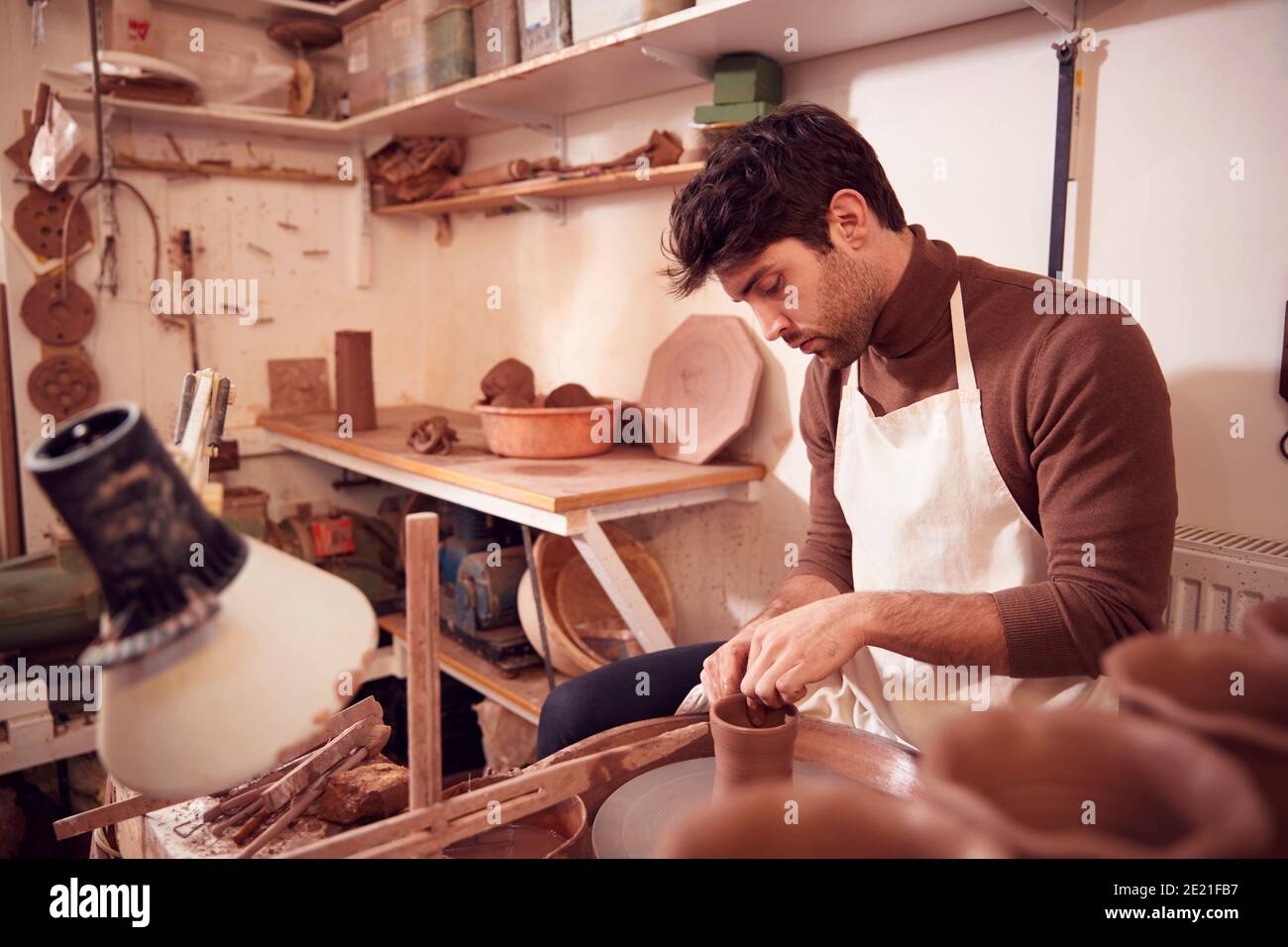 Male Potter Shaping Clay For Pot On Pottery Wheel In Ceramics Studio ...