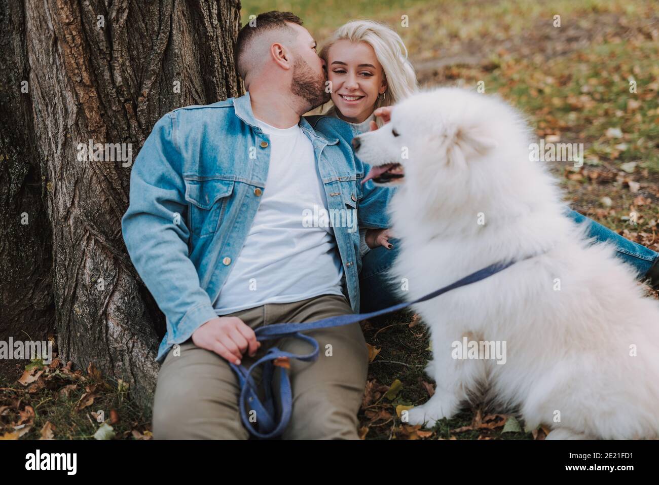 Smiling pretty young lady and her boyfriend with white furry puppy are ...