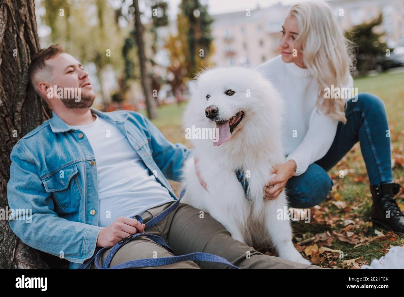 Happy pretty lady and her boyfriend hugging white furry playful puppy ...