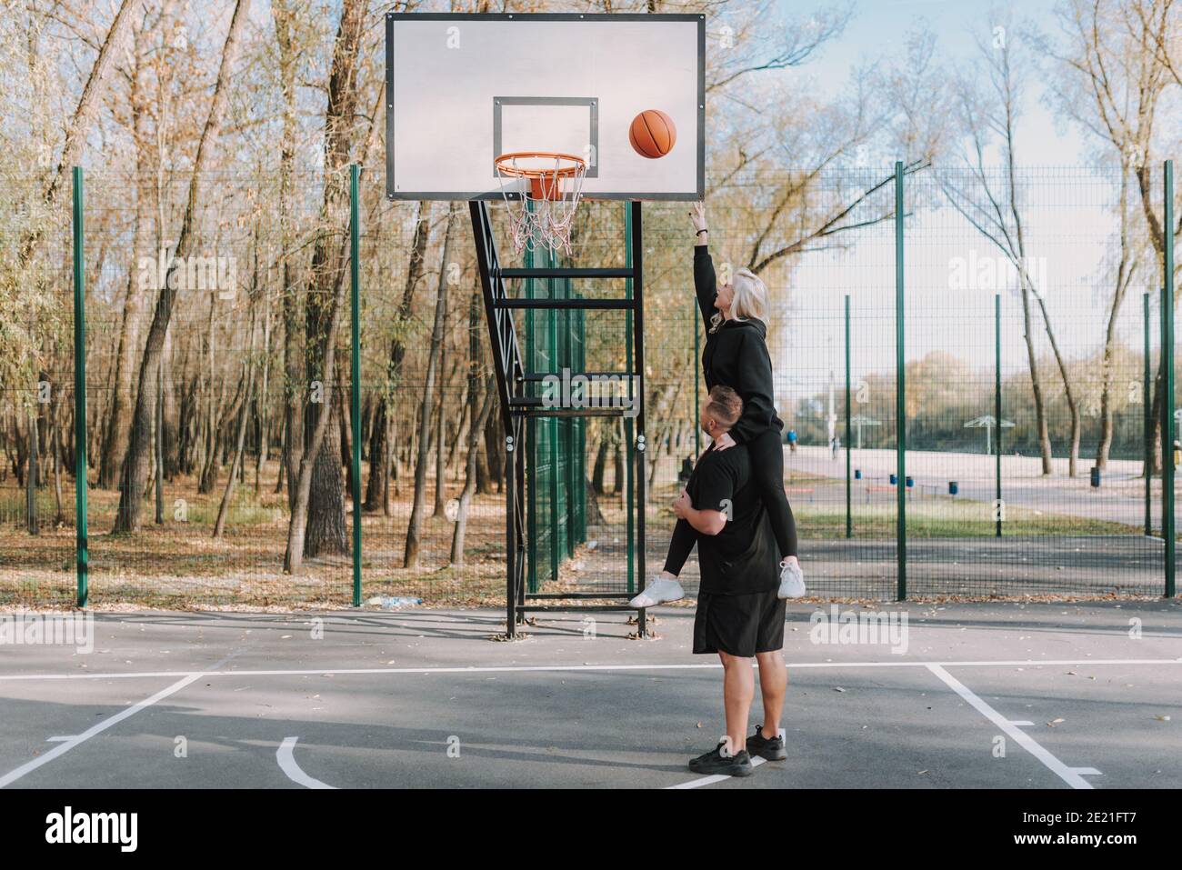 Full length of pretty lady throwing ball into basket while sitting on ...