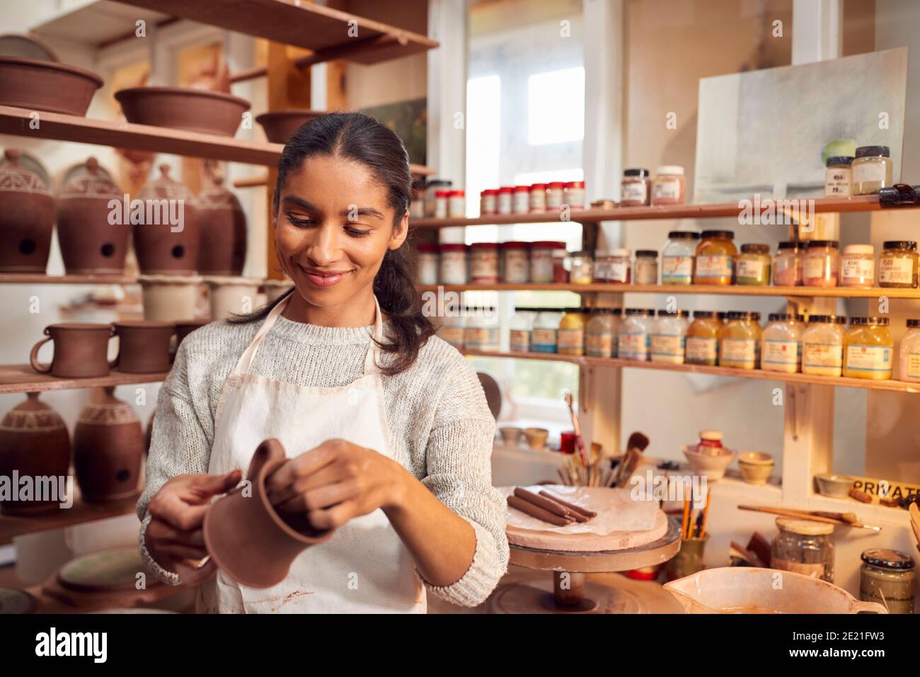 Female Potter Fitting Clay Handles To Mugs In Ceramics Studio Stock ...