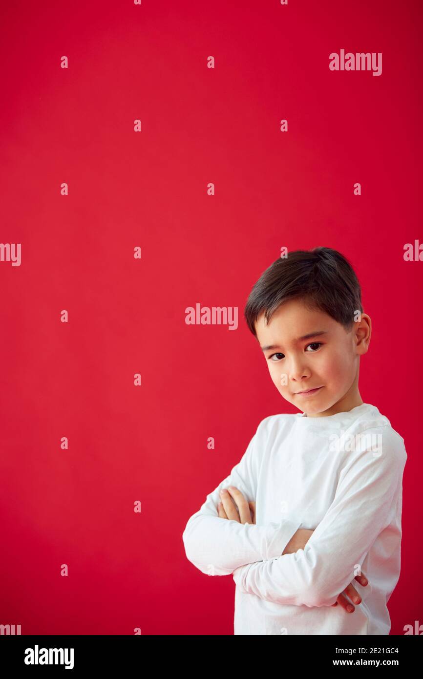 Portrait Of Young Boy With Folded Arms Against Red Studio Background ...