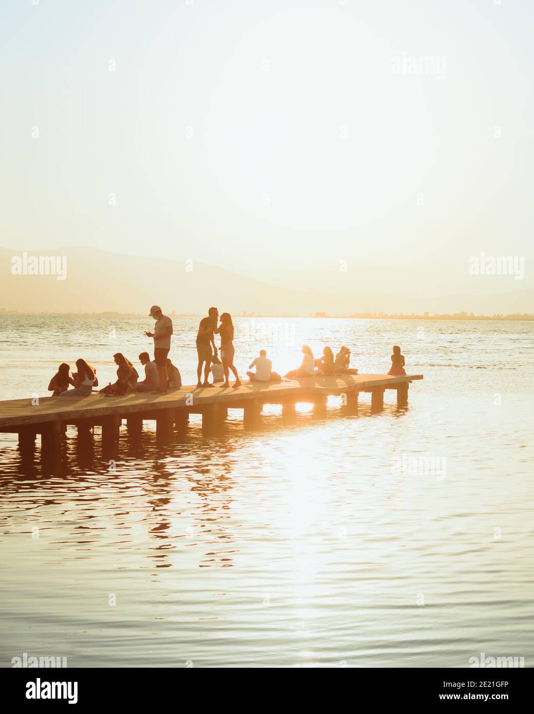 Dock in the sea with people watching the sunset Stock Photo - Alamy