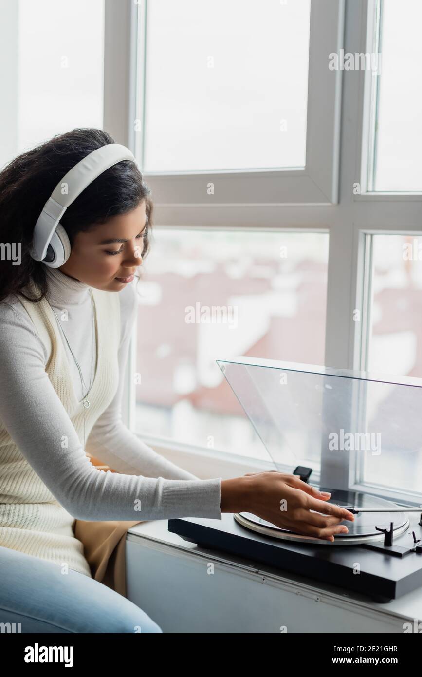young african american woman in wireless headphones turning on record ...