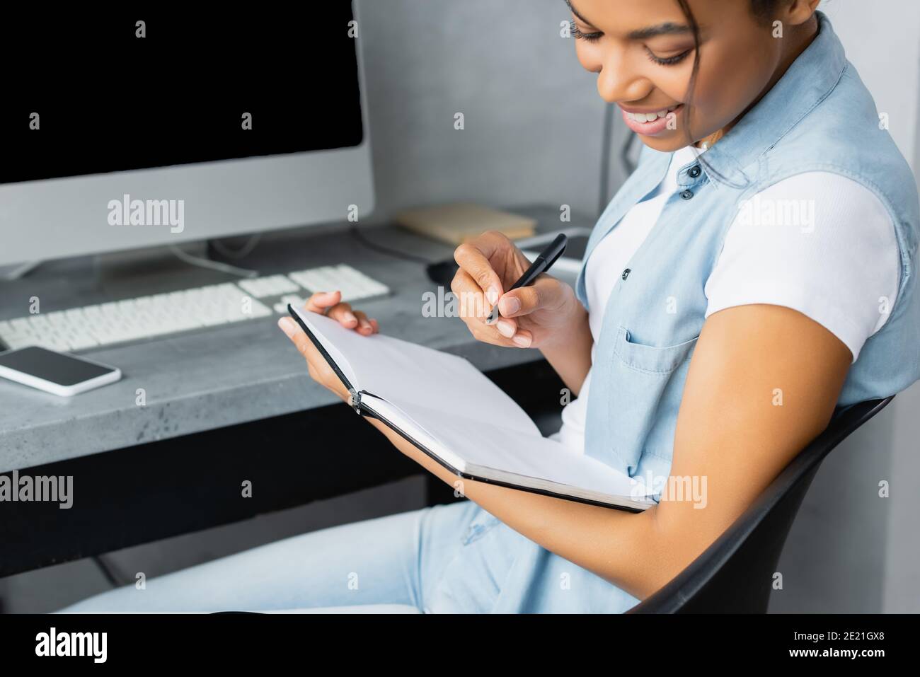 smiling african american freelancer holding notebook and pen near ... smiling african american freelancer holding notebook and pen near ...
