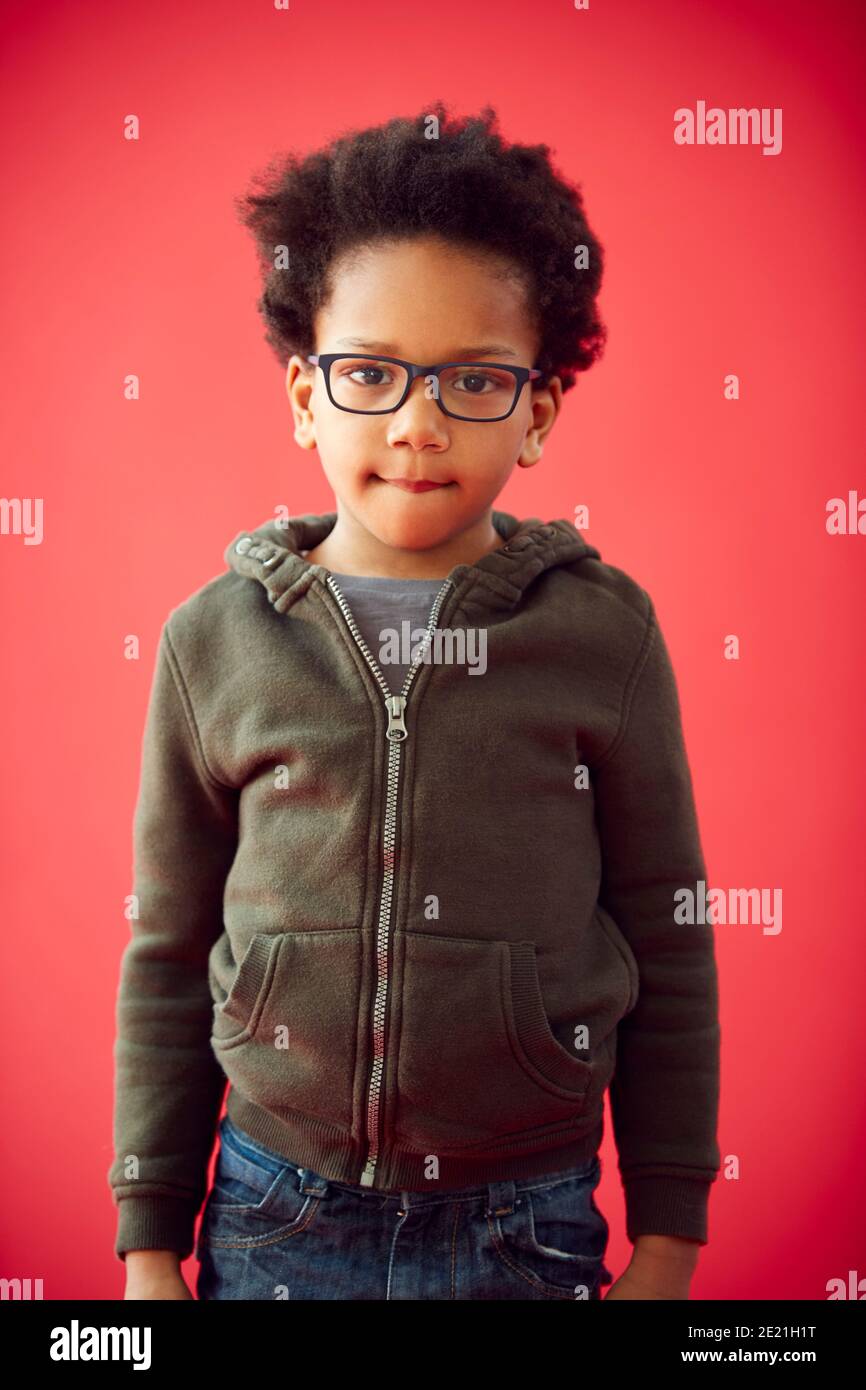 Portrait Of Young Boy Wearing Glasses Against Red Studio Background ...