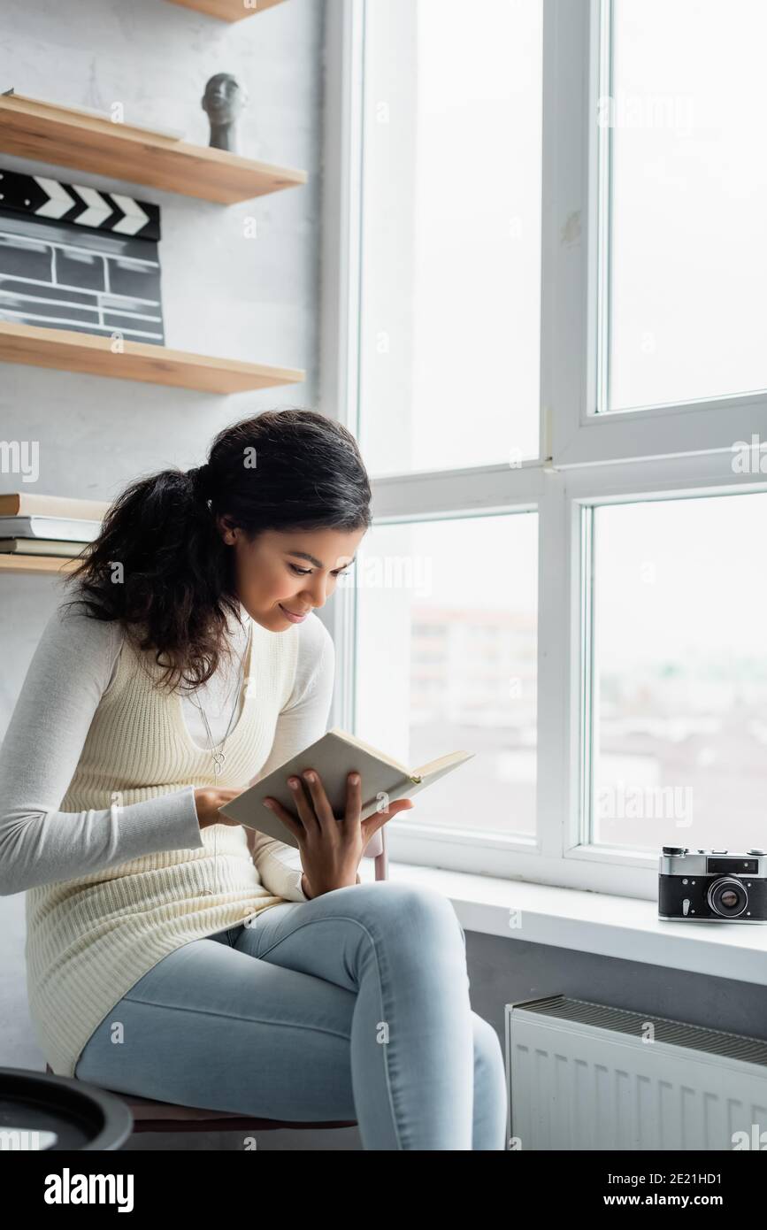 young african american woman reading book while sitting near vintage ...