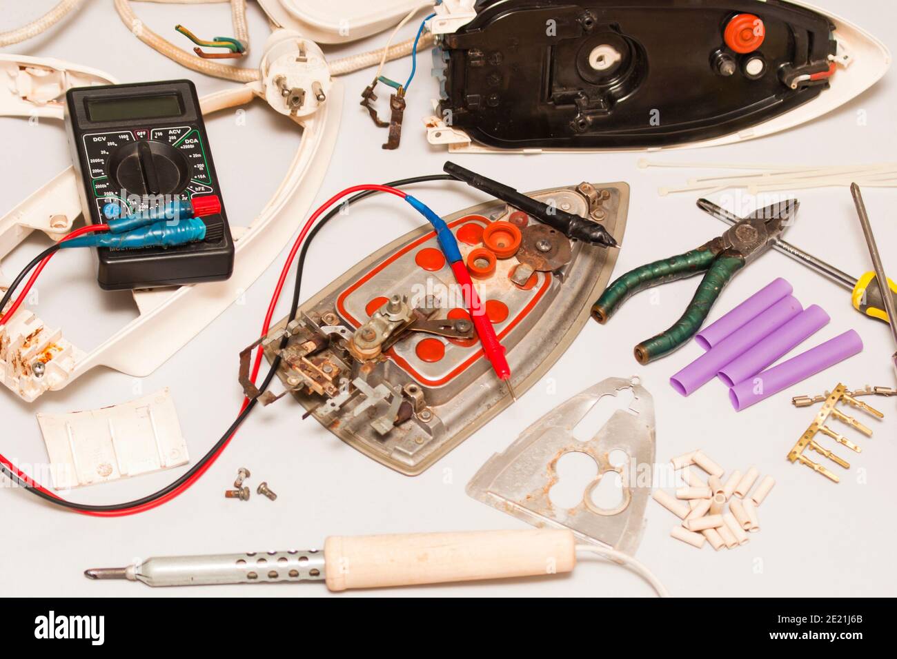 Repair of the iron. Disassembled faulty iron with tools on a white ...