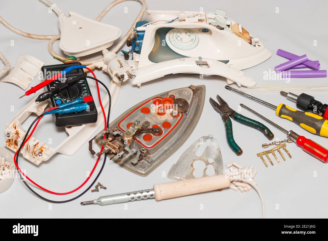 Repair of the iron. Disassembled faulty iron with tools on a white ...