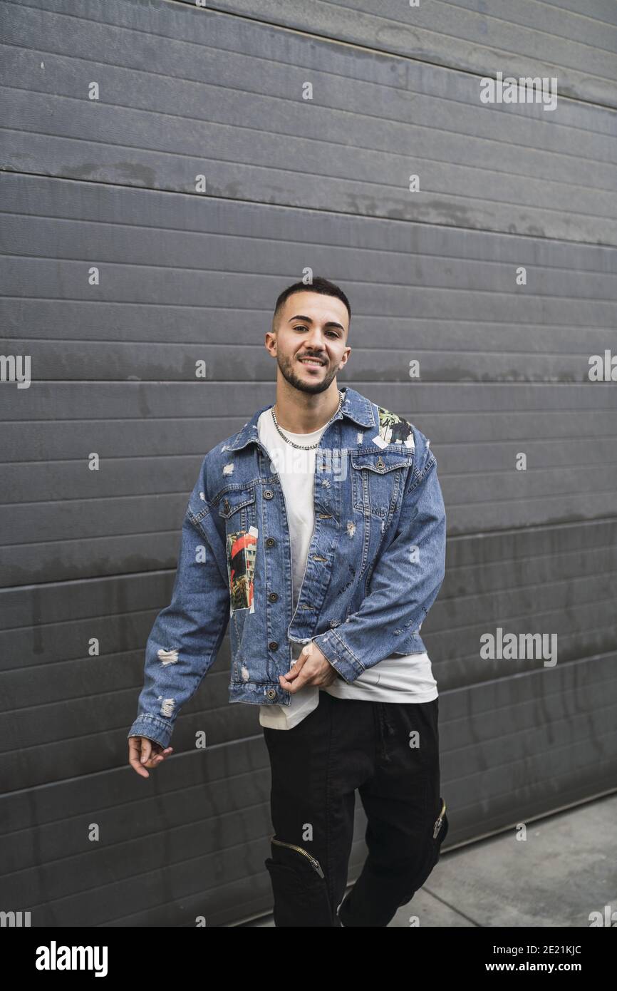 Vertical shot of a young trendy male in streetwear posing and smiling ...