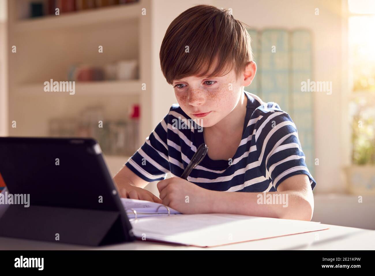 Boy Sitting At Kitchen Counter Doing Homework Using Digital Tablet ...