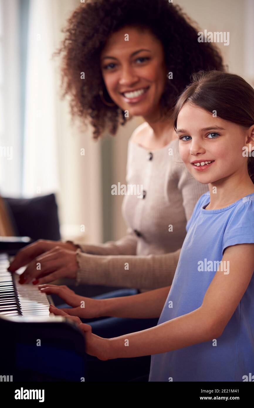 Portrait Of Young Girl Learning To Play Piano Having Lesson From Female ...