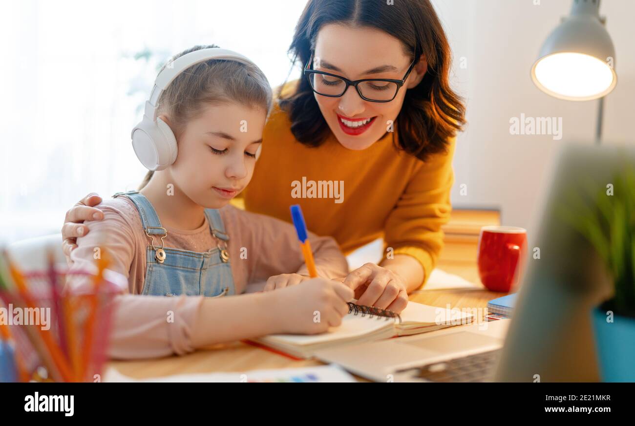 Back to school. Happy child and adult are sitting at desk. Girl doing ...