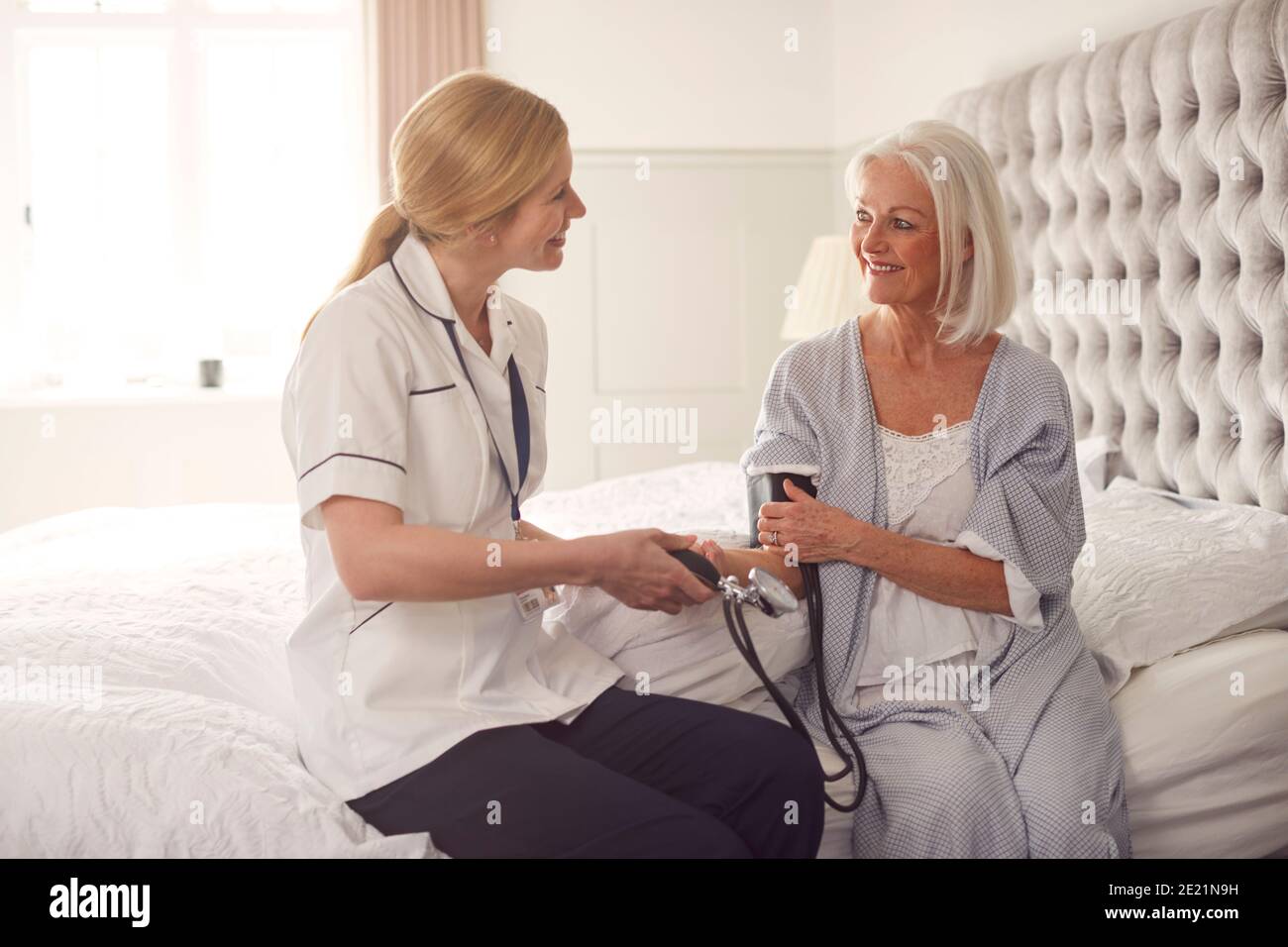 Female Doctor Making Home Visit To Senior Woman In Bedroom For Blood ...
