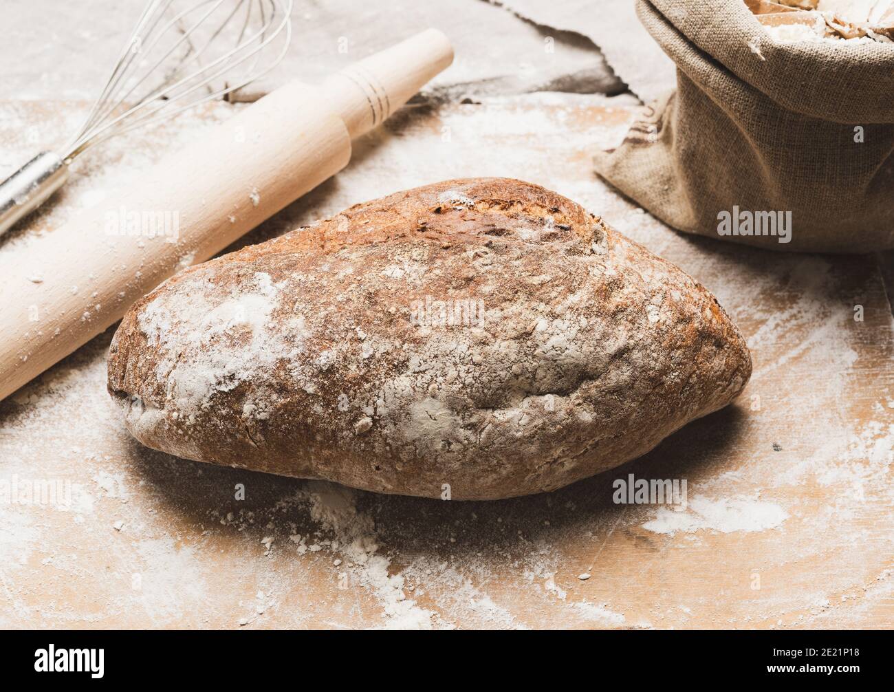 baked oval rye flour bread in a metal baking sheet on the table, top ...