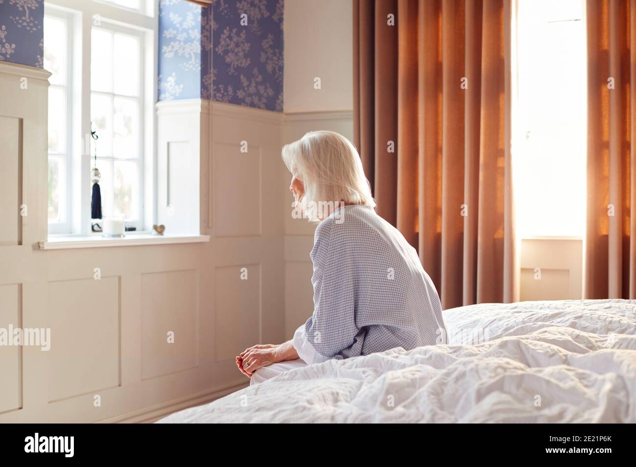 Woman Sitting On Edge Of Bed