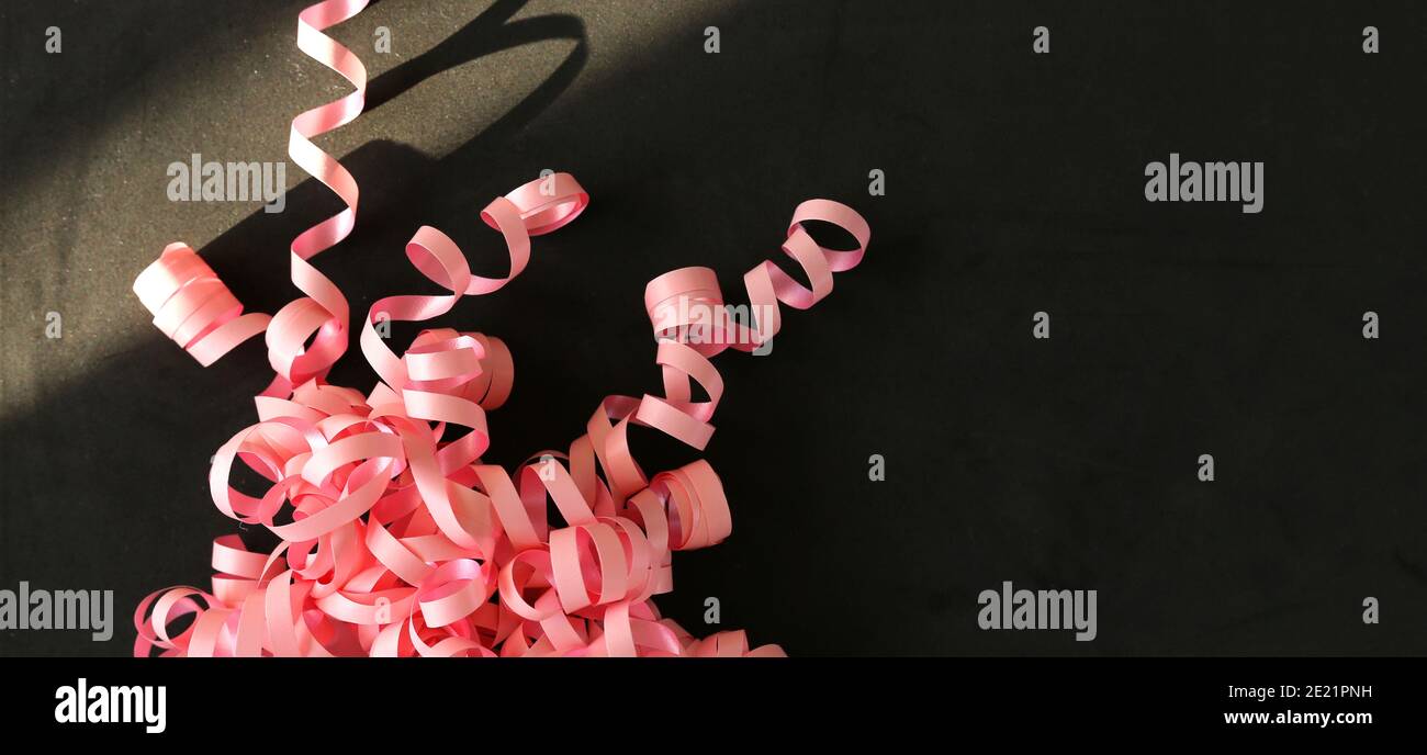 Pink serpentine streamer on black background Party accessory Stock ...