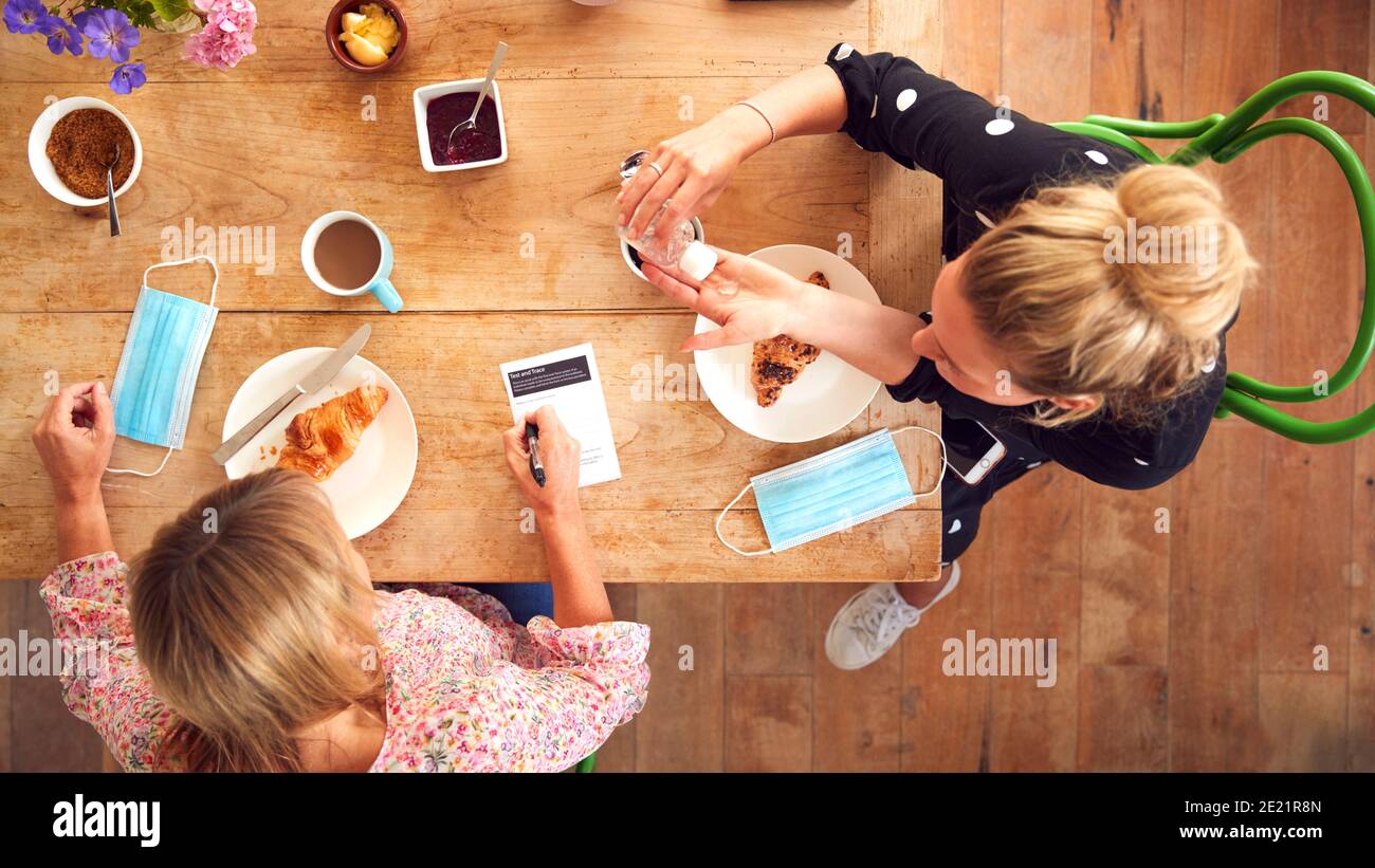 Two Female Friends In Coffee Shop Use Hand Sanitizer And Fill In Test ...