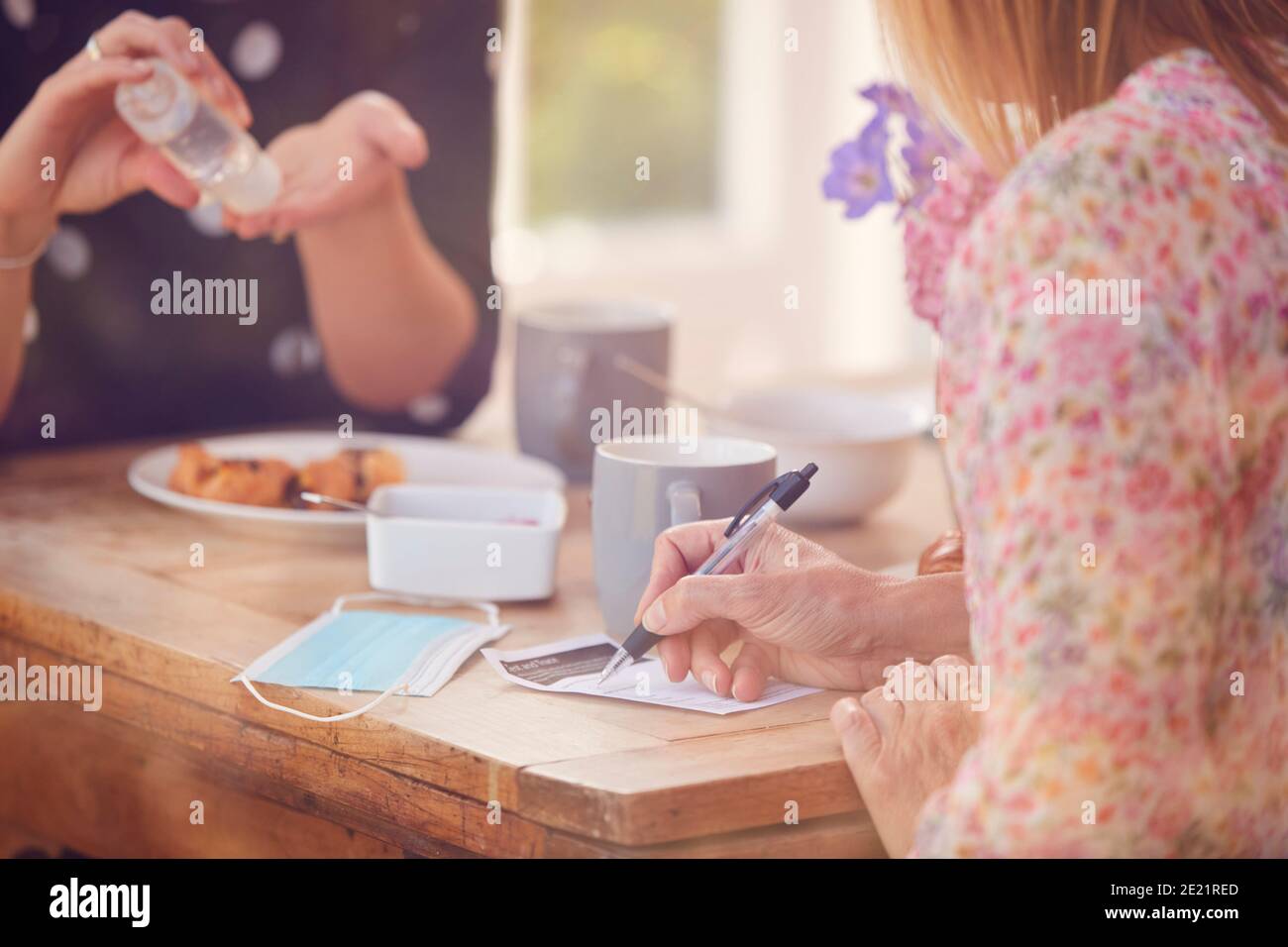 Two Female Friends In Coffee Shop Use Hand Sanitizer And Fill In Test ...