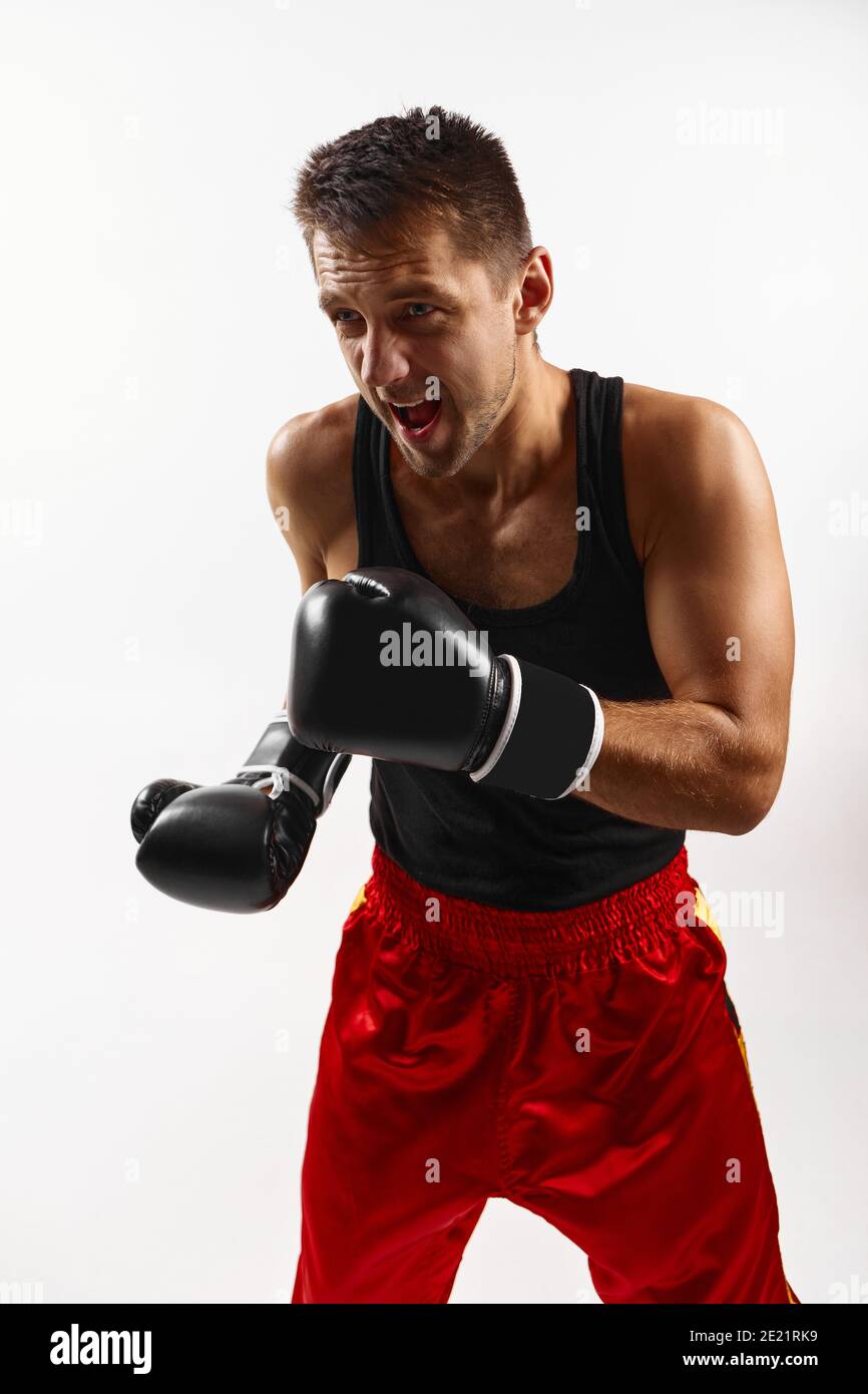 Aggressive boxer in black boxing gloves punching isolated on white ...