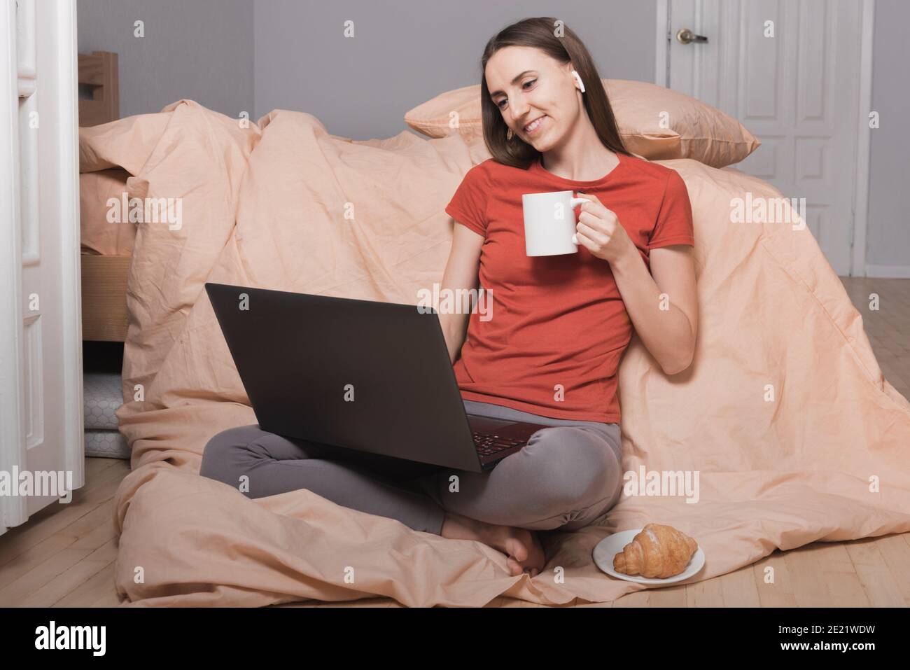 Smiling girl working from home on laptop computer while sitting on a ...