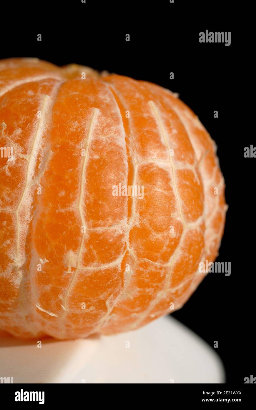 Juicy peeled mandarin against dark background closeup. Shallow depth of ...