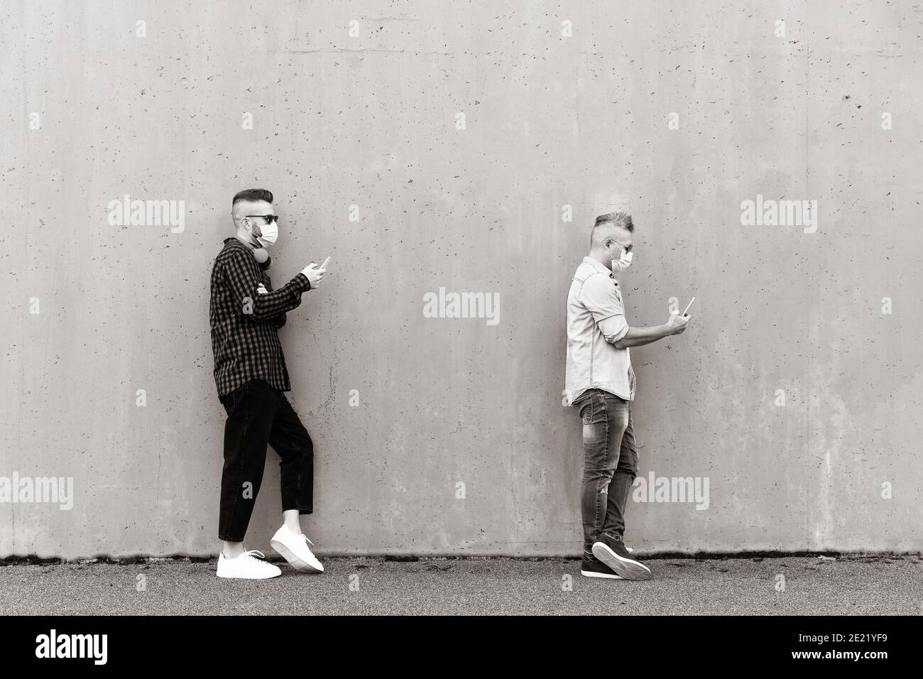 Cool men in a line using mobile phones while keeping social distance ...